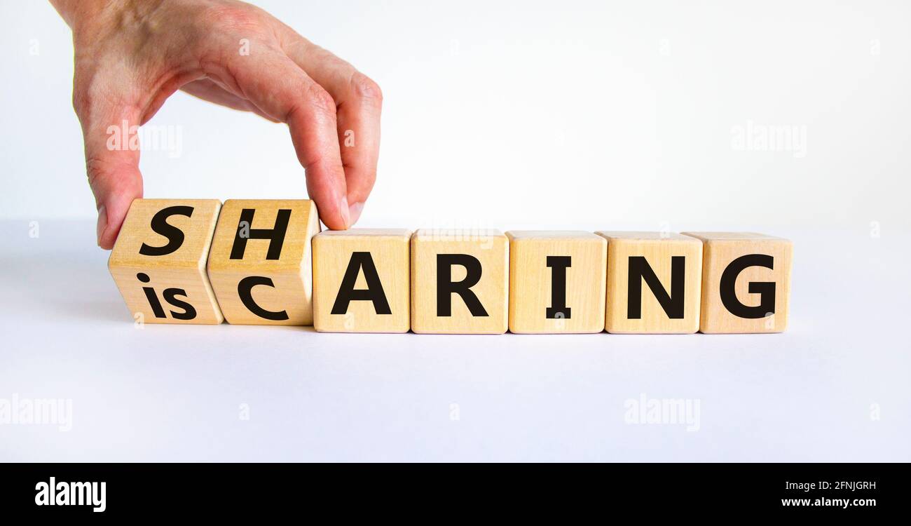 Sharing is caring symbol. Businessman turns wooden cubes with words ...