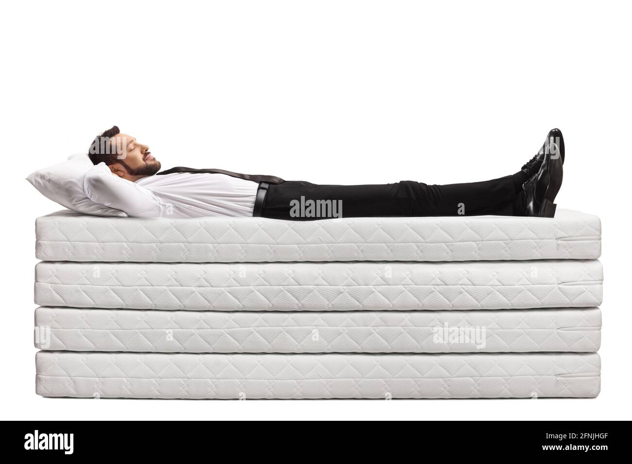 Businessman lying on a pile of mattresses with clothes and shoes ...