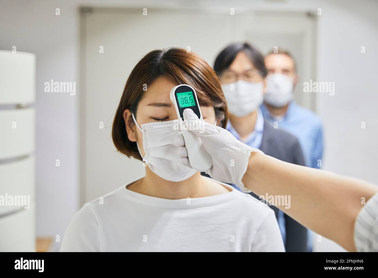 Checking body temperature in the office Stock Photo - Alamy