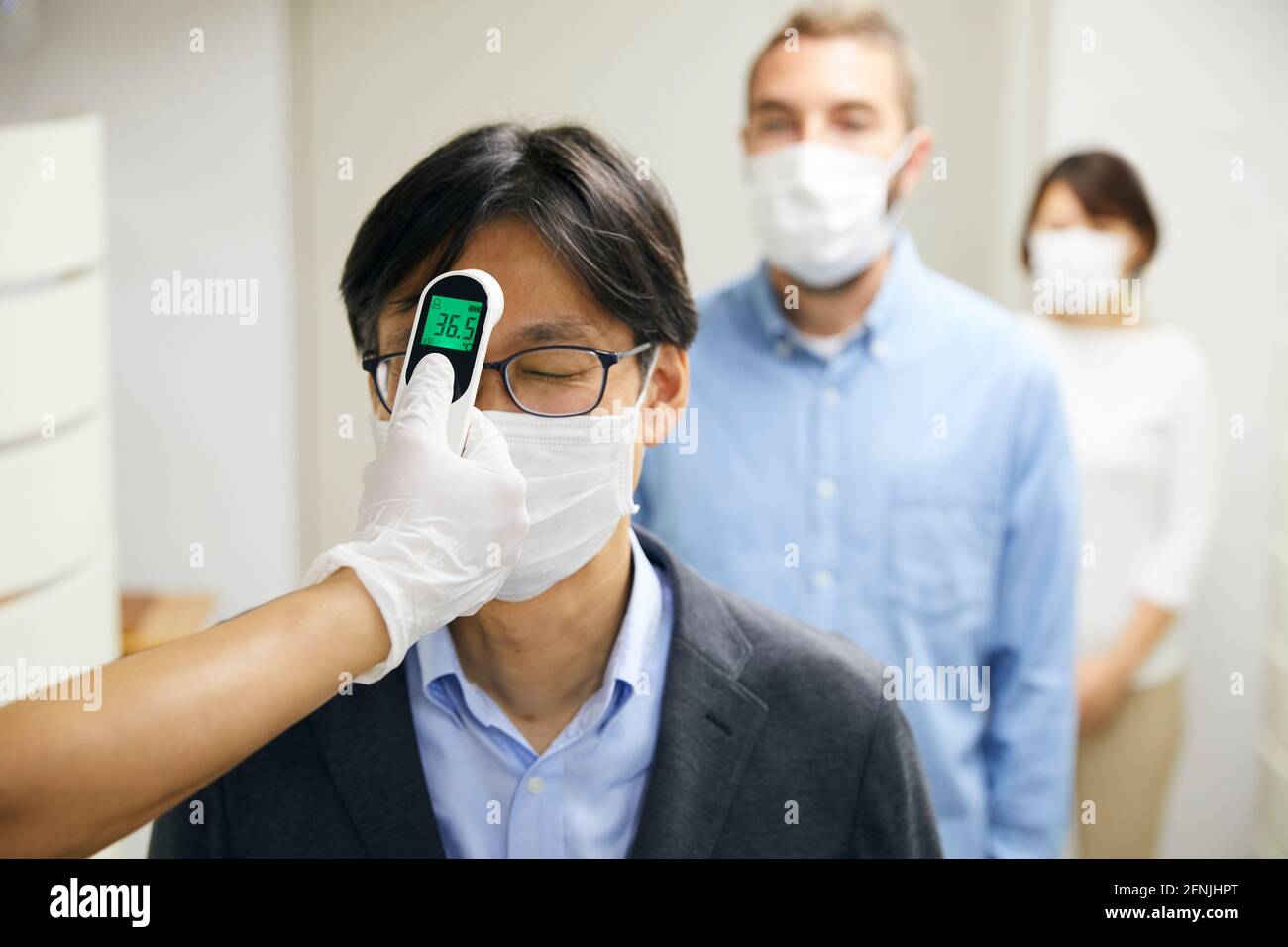 Checking body temperature in the office Stock Photo - Alamy