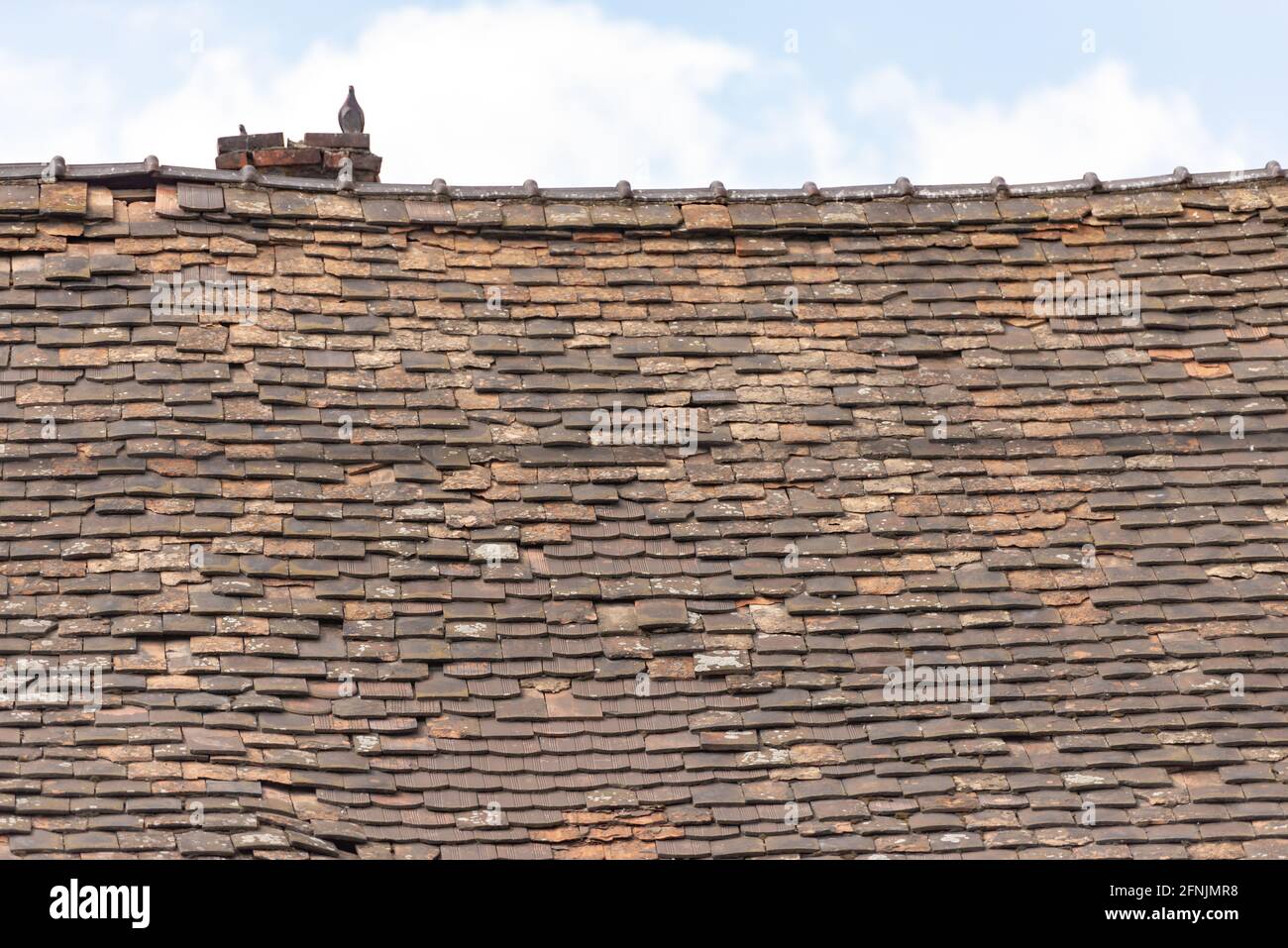 The roof is made of clay tiles. Shingles close-up with destroyed areas ...