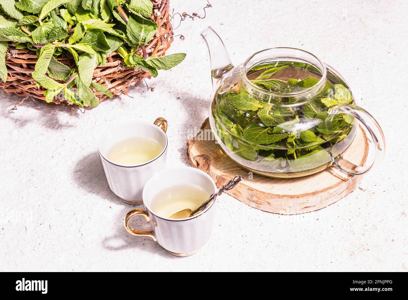 Teatime concept. Aromatic mint tea, ceramic cups on stands. Modern hard ...