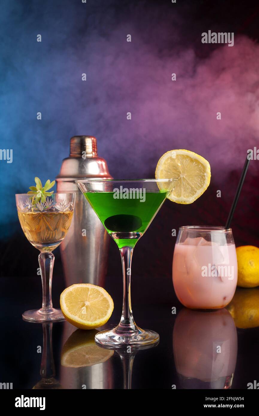 Vertical shot of colorful cocktails on a bar table with smoke and ...