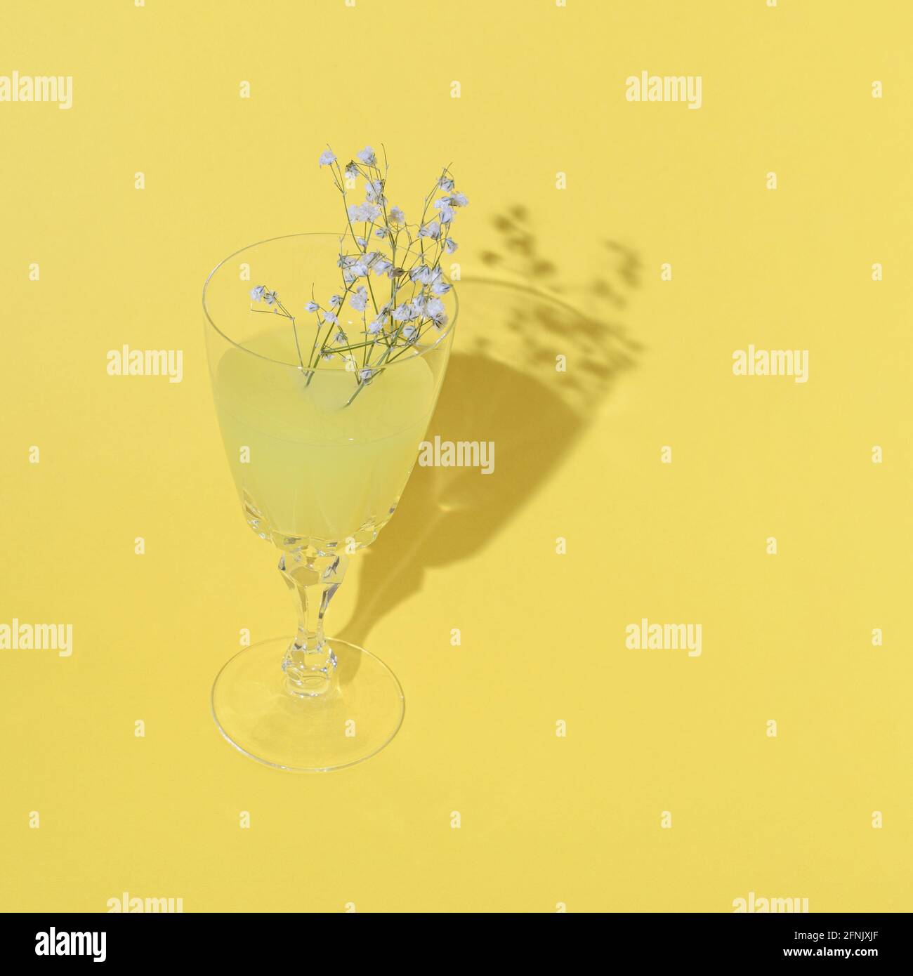 Yellow lemonade drink on a yellow background with flowers in glass ...