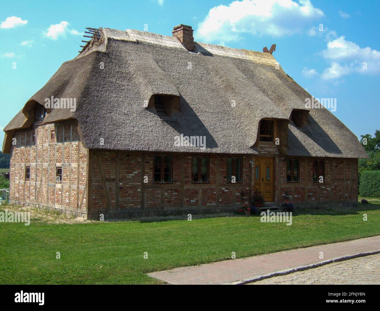 Large brick half-timbered house with big thatched roof on a green ...
