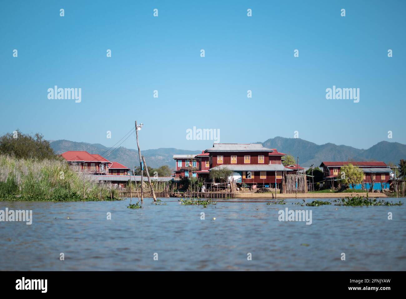 Red elevated buildings by the riverside of the canals at Inle Lake ...