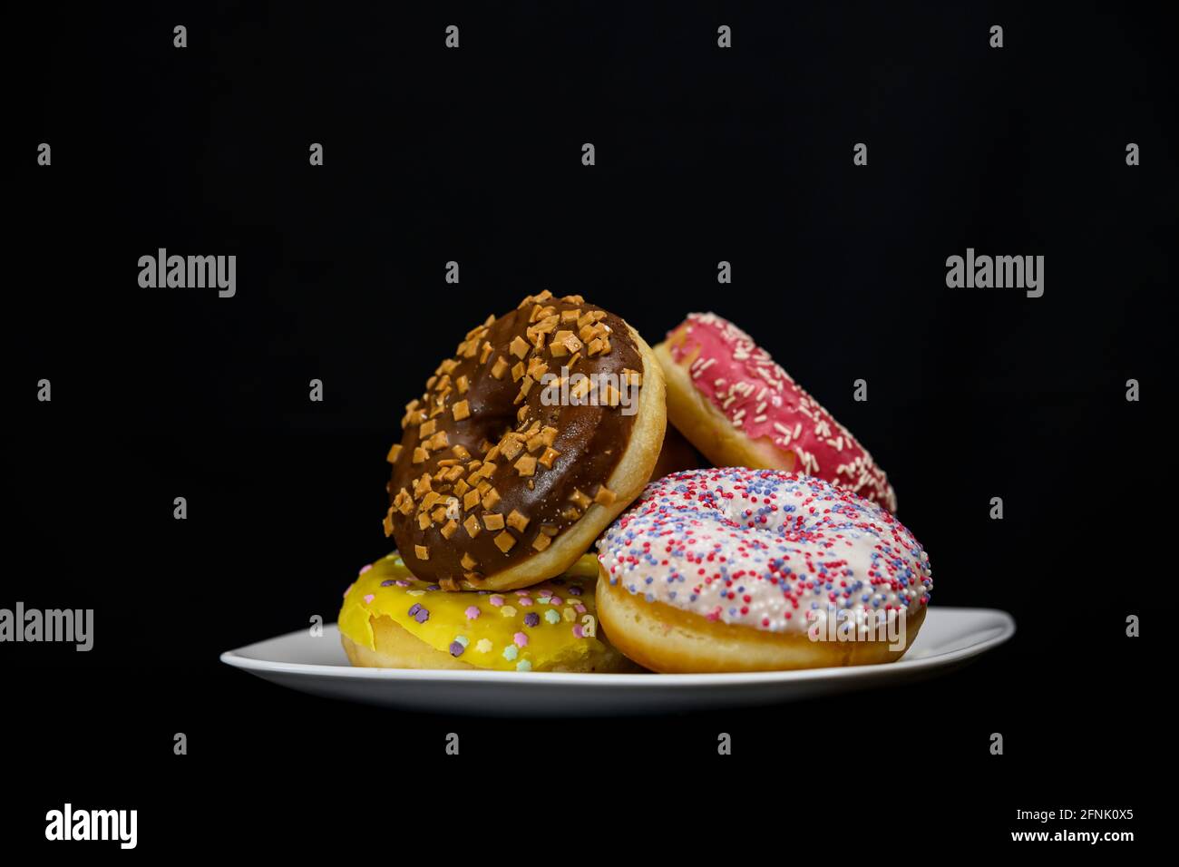 Donuts of different colors in plate close up Stock Photo - Alamy