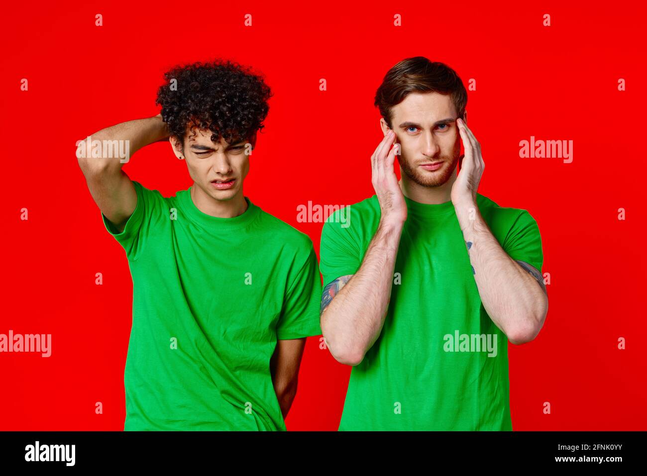 two friends in green t-shirts are standing next to tin with their hands ...