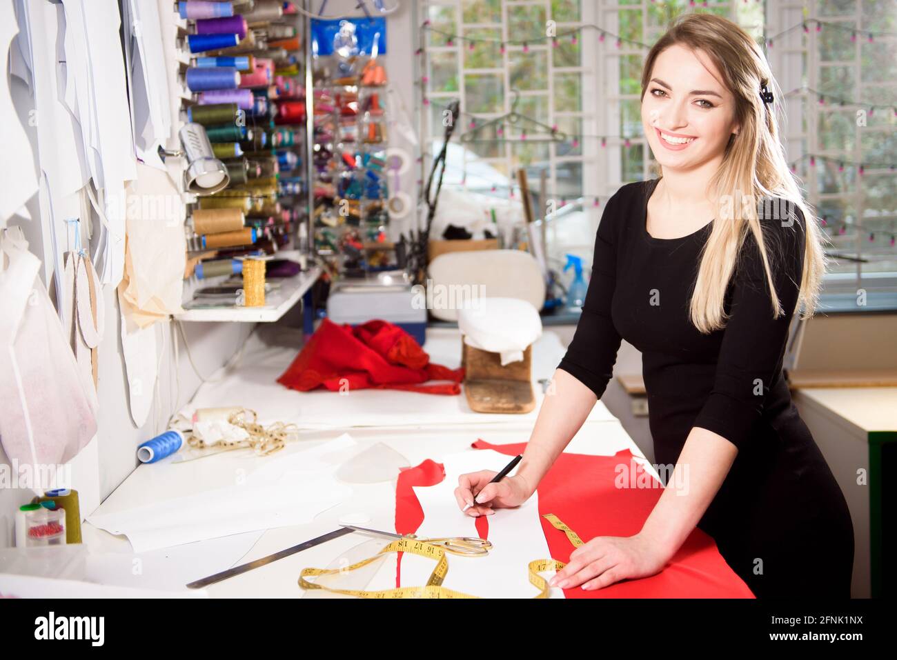 Young dressmaker woman sews clothes on sewing machine Stock Photo - Alamy