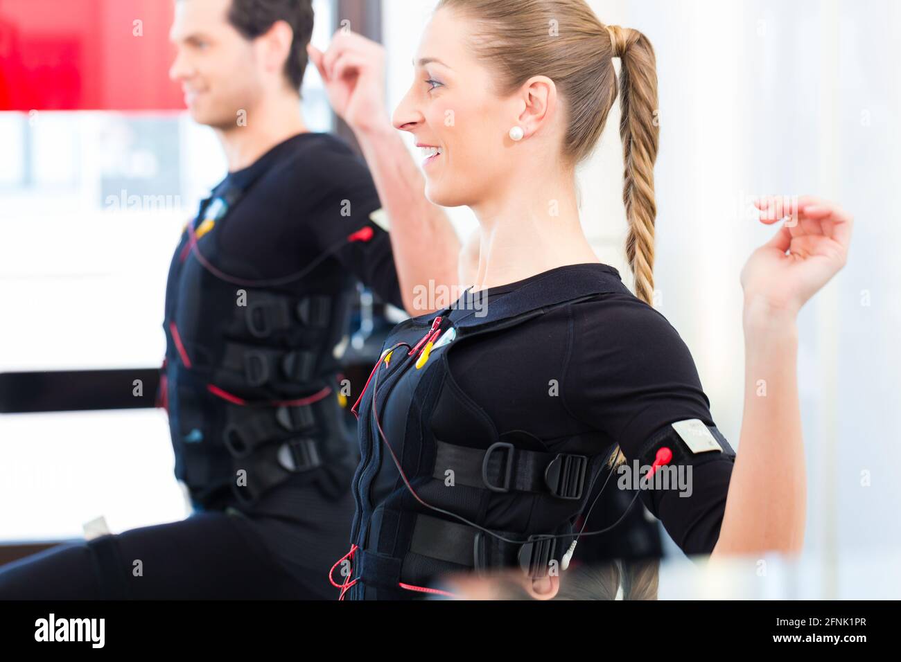 Female coach giving man and woman ems electro muscular stimulation exercise Stock Photo - Alamy