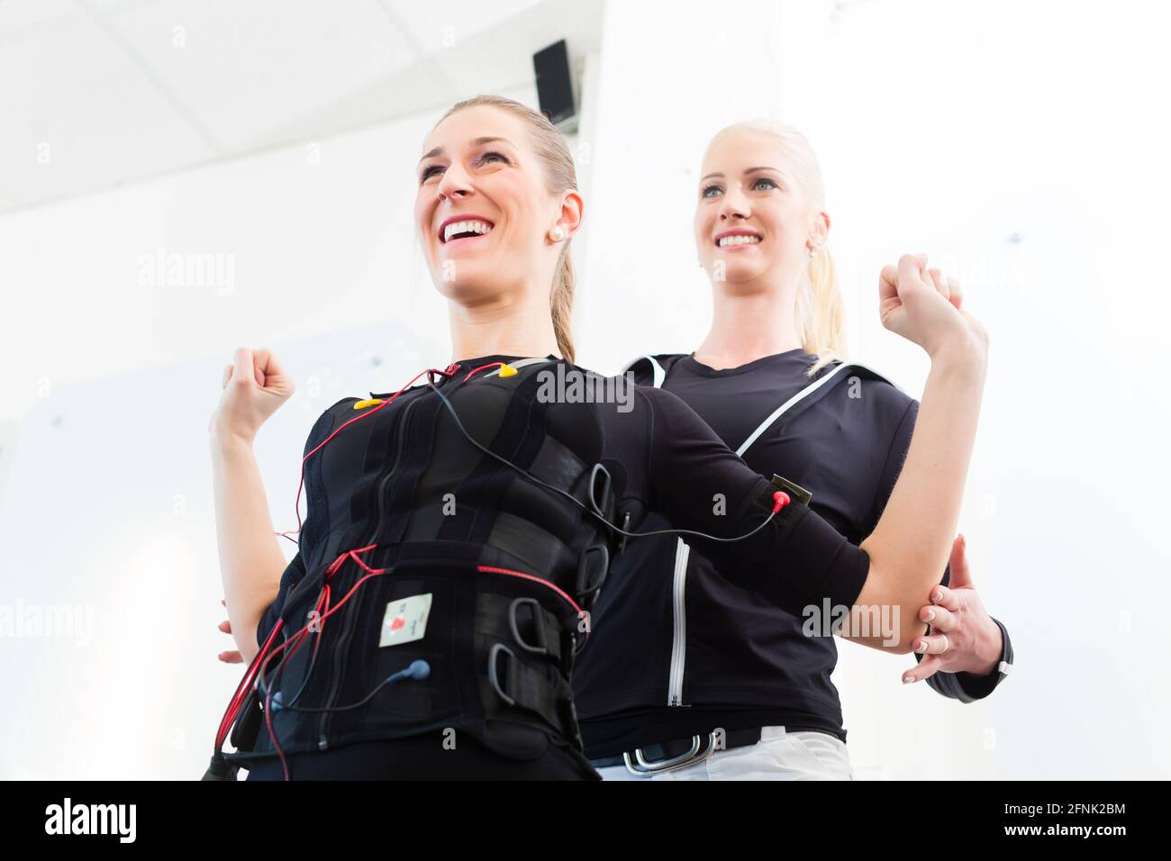 Female personal trainer giving man ems electro muscular stimulation ...
