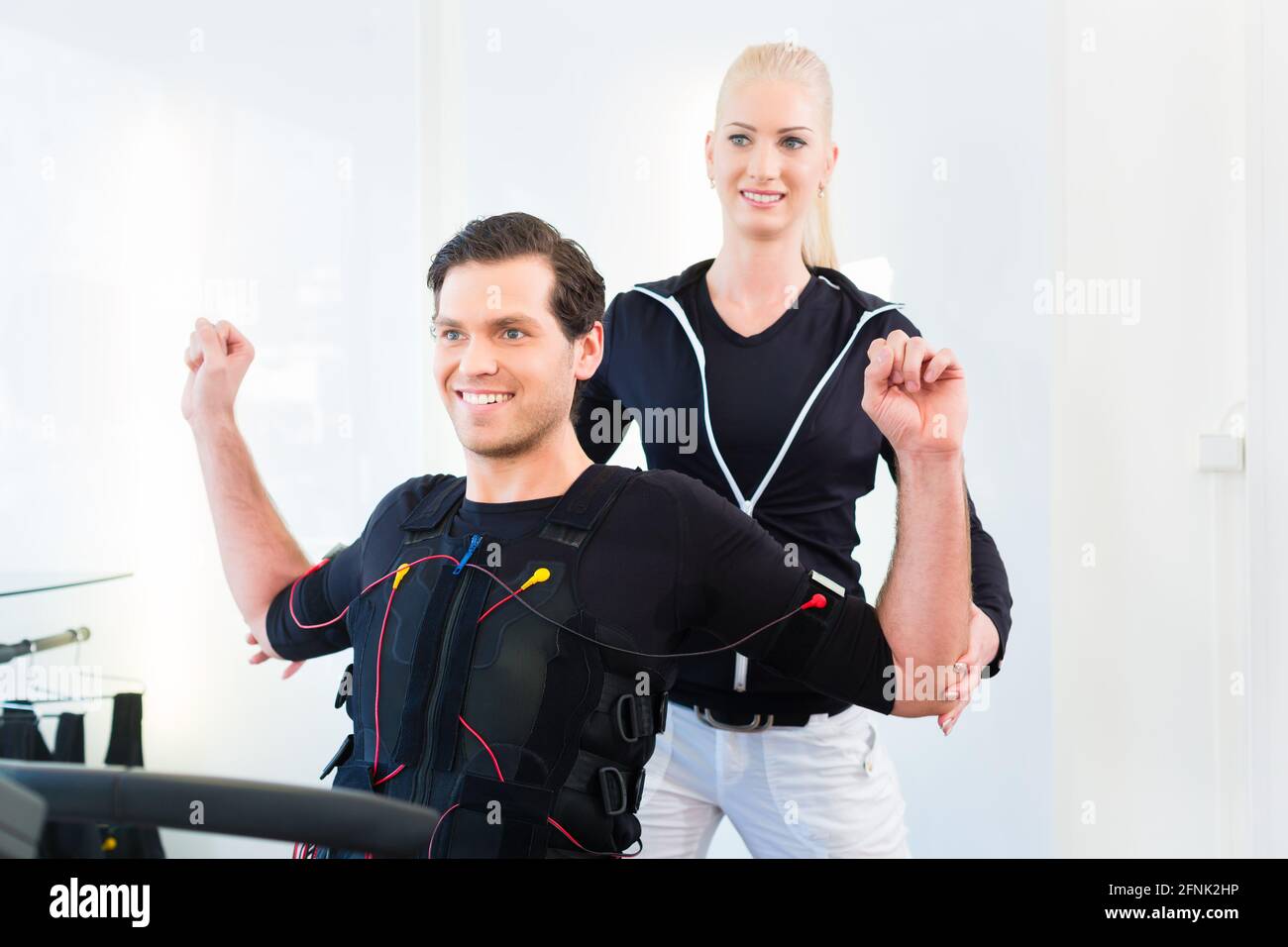 Female personal trainer giving man ems electro muscular stimulation ...