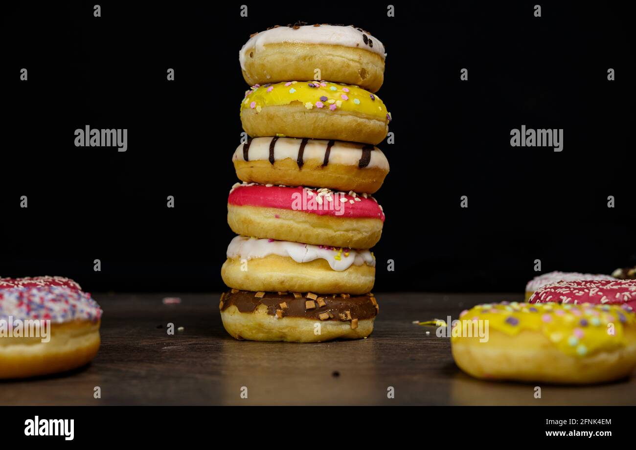 Donuts of multiple colors piled up close up Stock Photo - Alamy