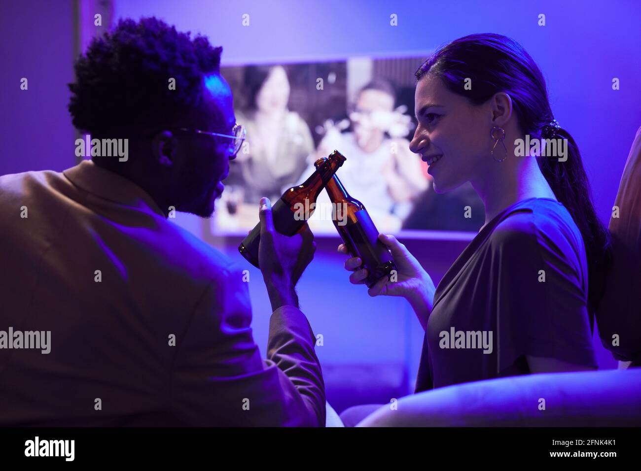 Side view portrait of coupe drinking beer while enjoying party at home ...