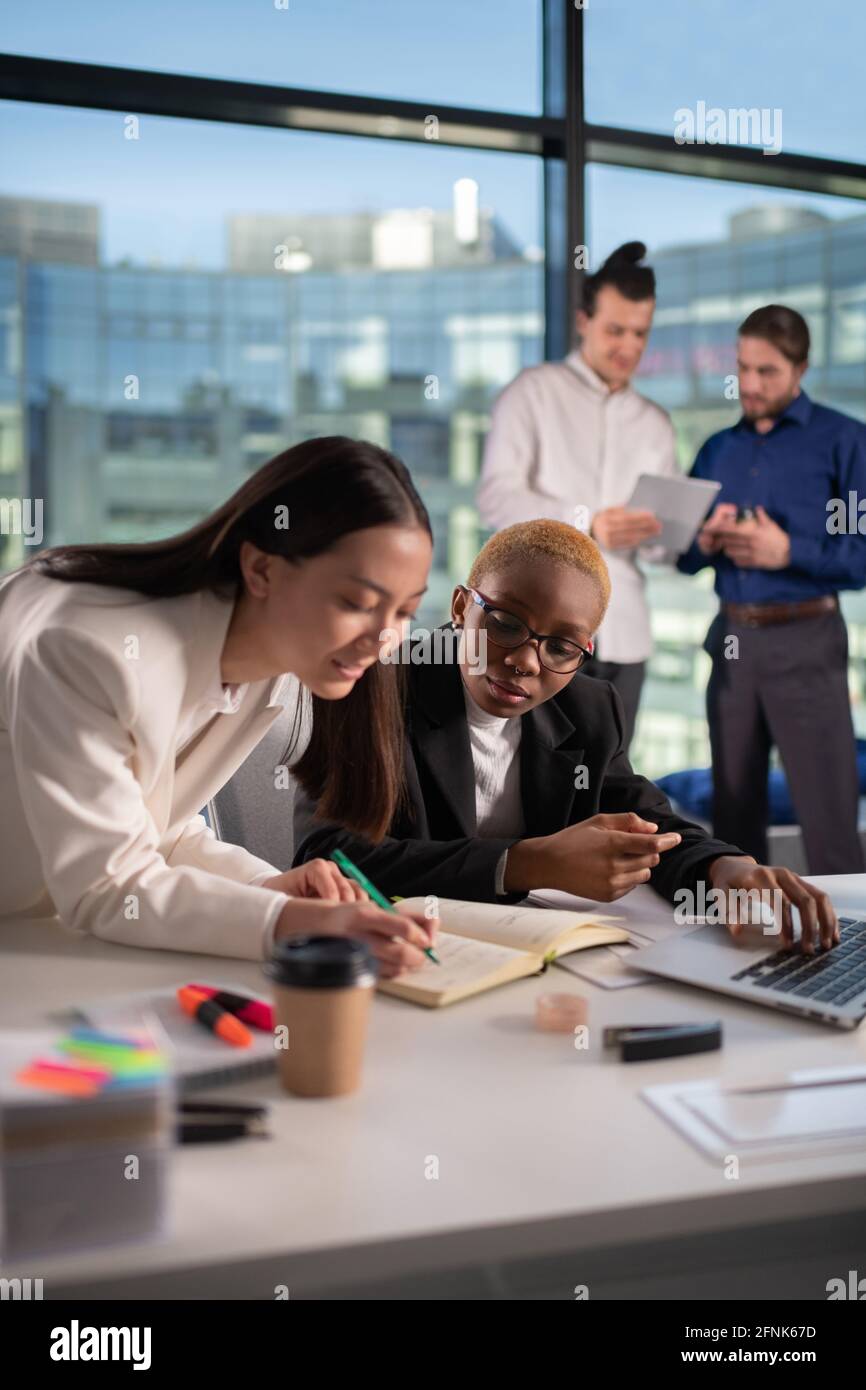 Multiracial colleagues making notes together Stock Photo - Alamy