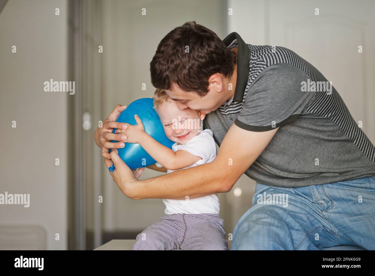 father and son laugh and hug with blue balloon Stock Photo - Alamy