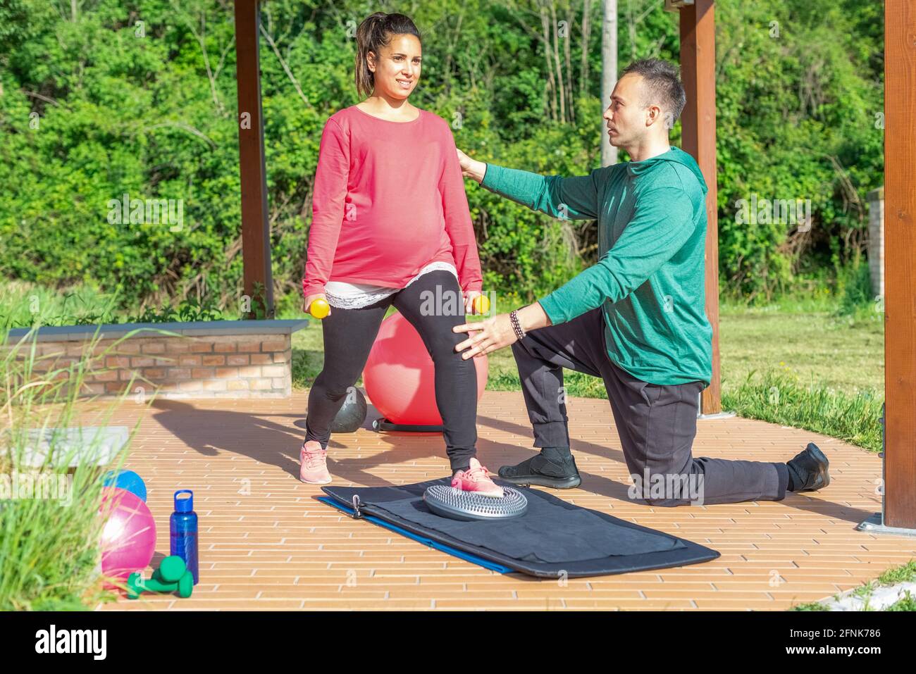 Young pregnant woman training arms with weights lifting standing on a ...