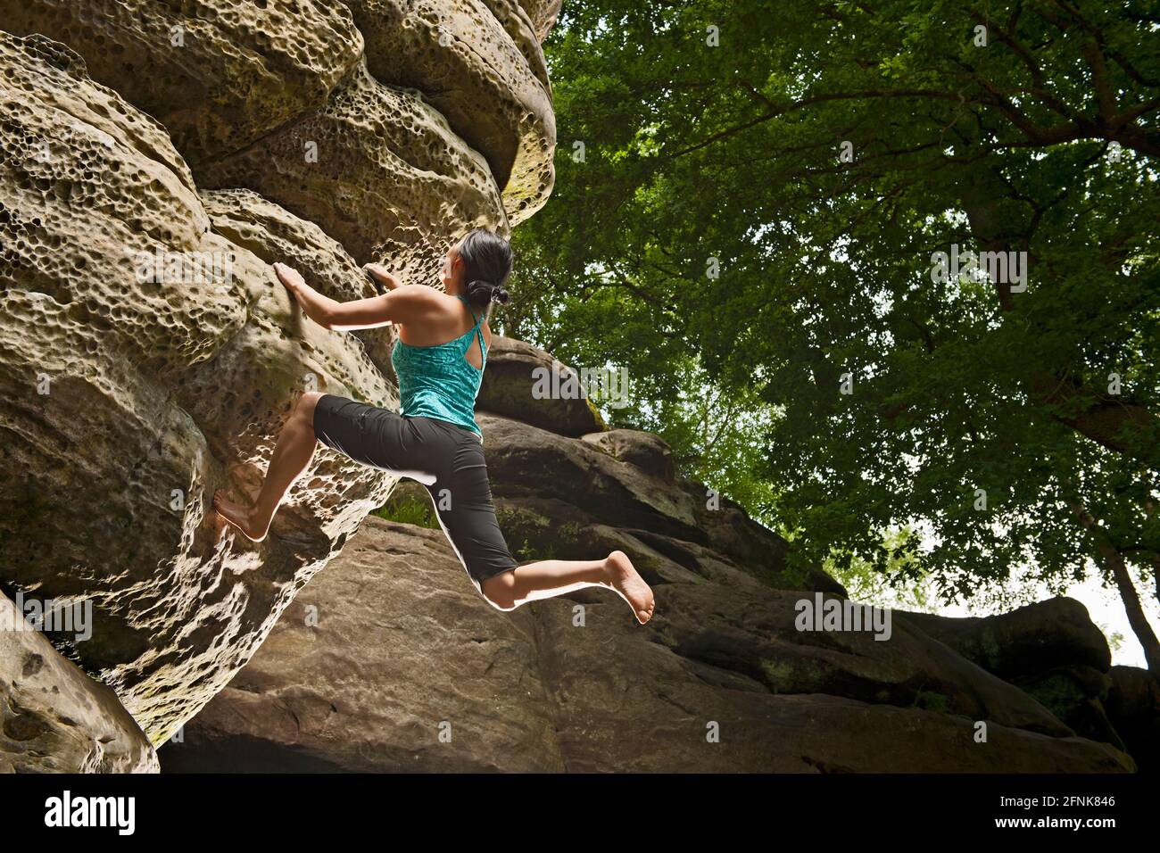 Woman bouldering on the sandstone rocks at Harrison's Rock in England ...