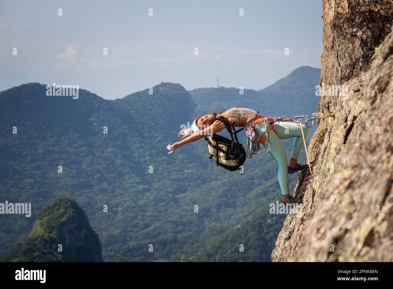Beautiful view to female acrobat climber bending body back on mountain ...