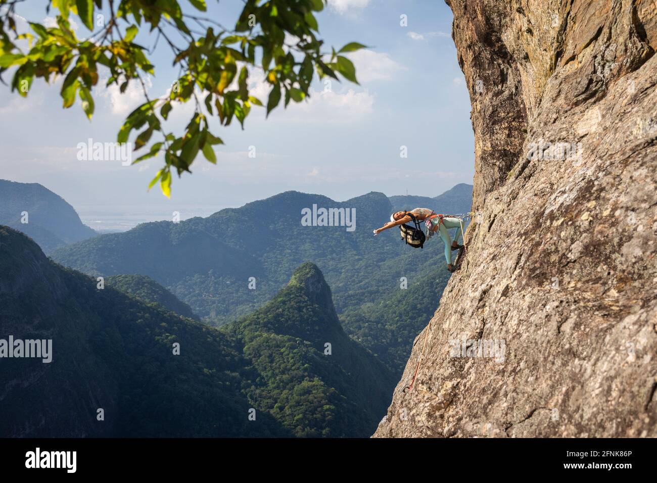 Beautiful view to female acrobat climber bending body back on mountain ...