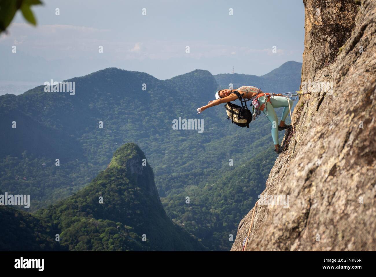 Beautiful view to female acrobat climber bending body back on mountain ...