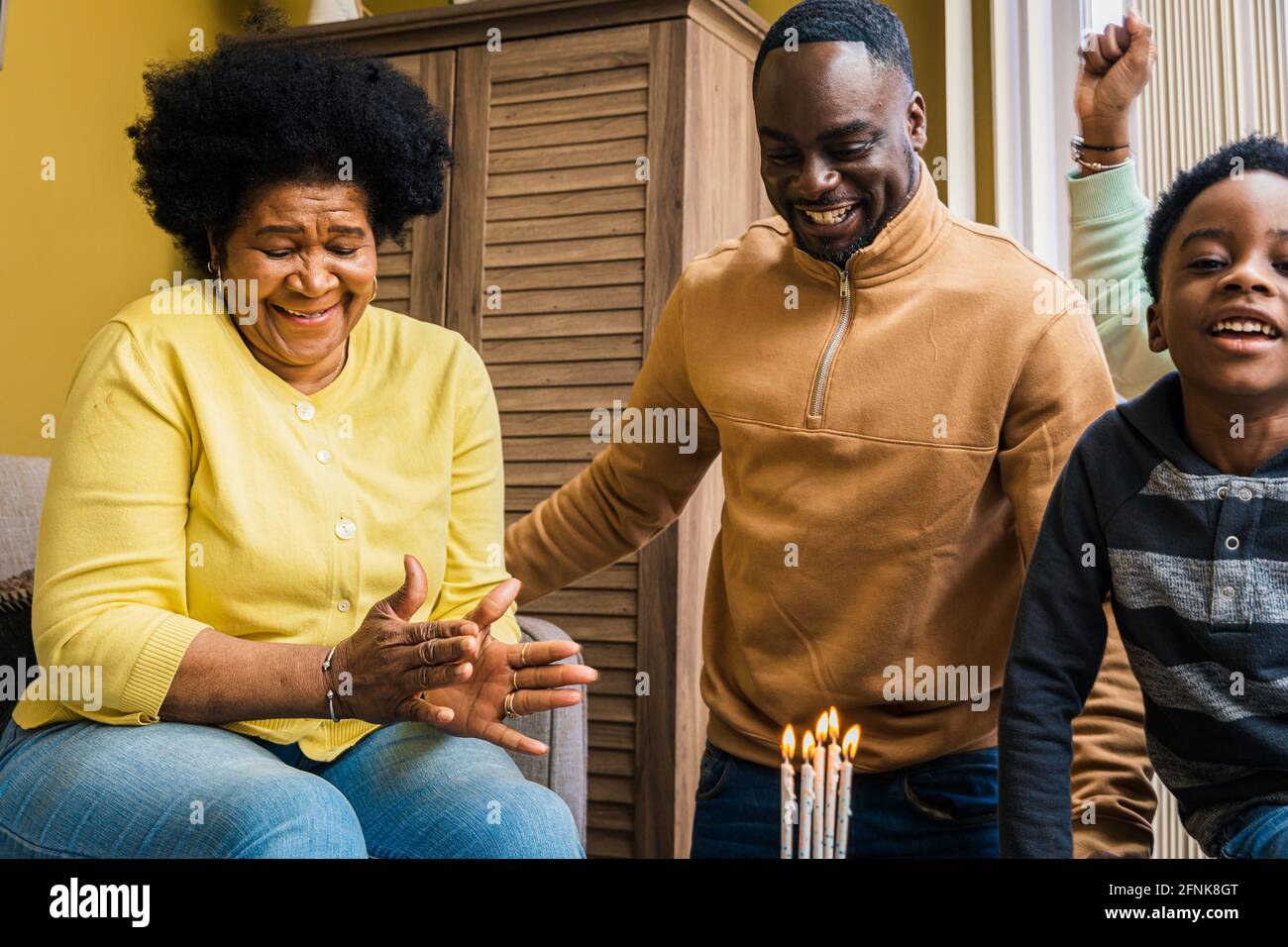 Happy multi-generational family celebrating birthday together at home ...