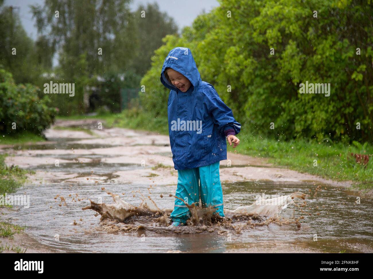 Happy child is jumping in a puddle Stock Photo - Alamy