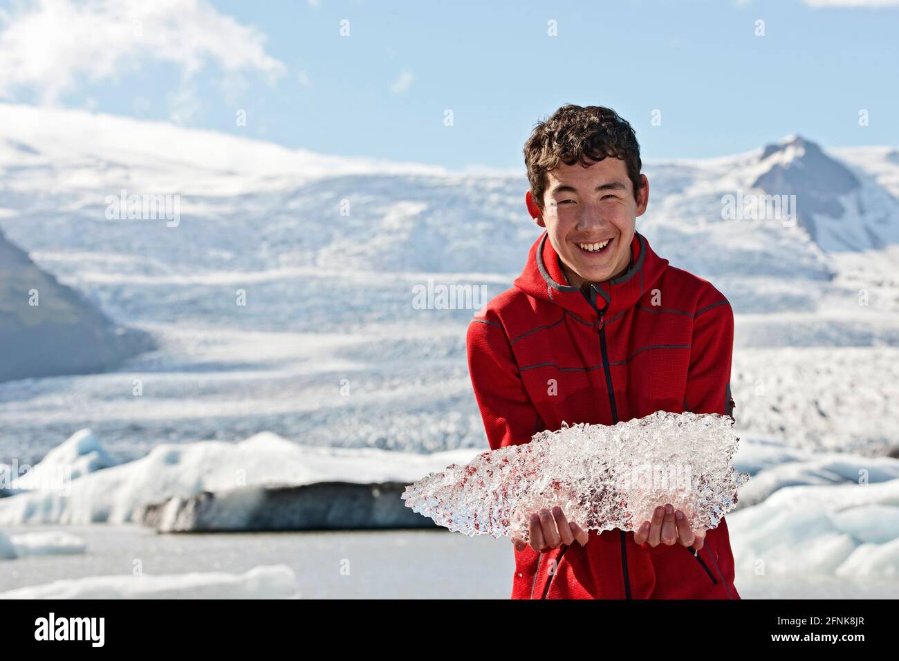 teenage boy holding up ice from glacier lagoon in Iceland Stock Photo ...
