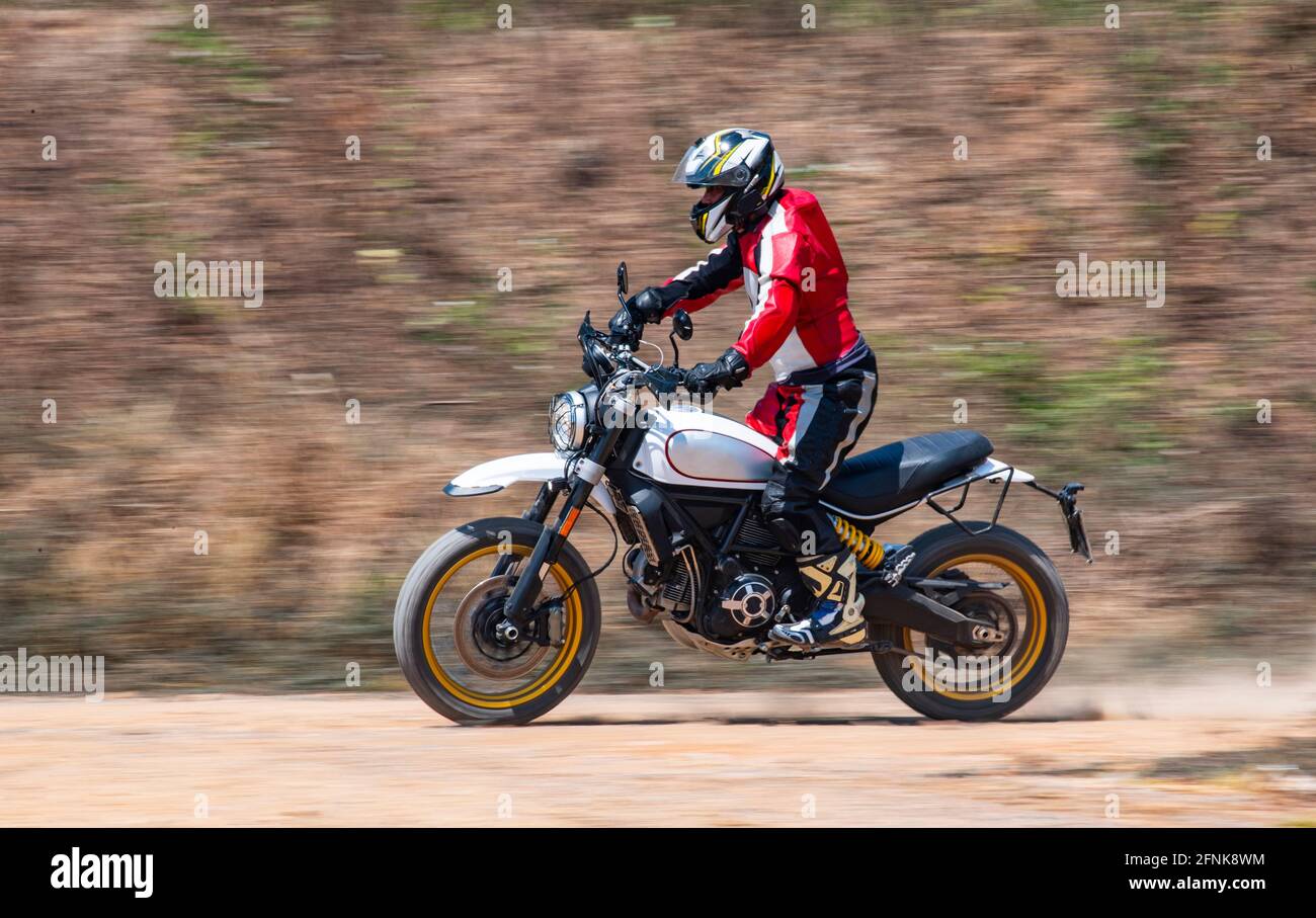 man riding his scrambler type motorcycle on dirt track in Thailand ...