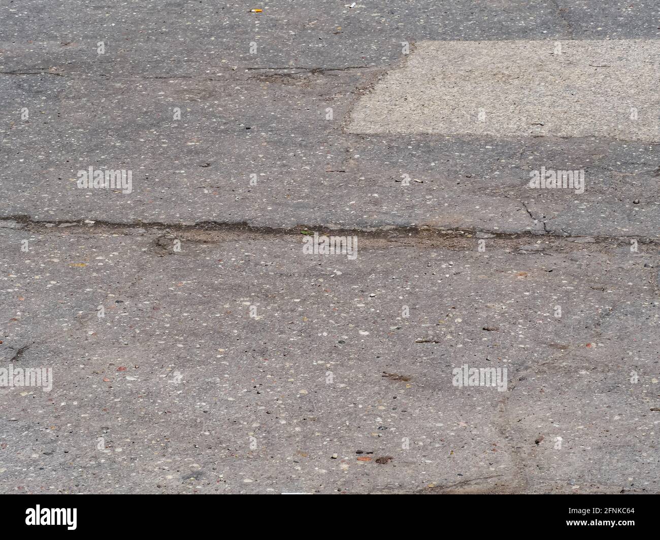 Closeup of rough textured asphalt with cracks on it in the daylight ...