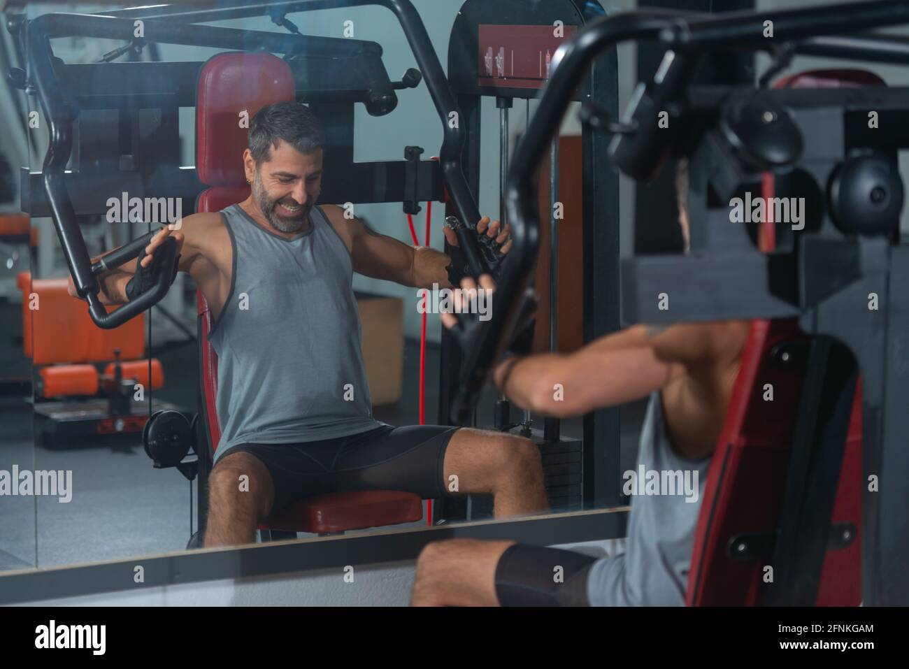Picture in mirror of a strong muscular fit man training back muscles ...