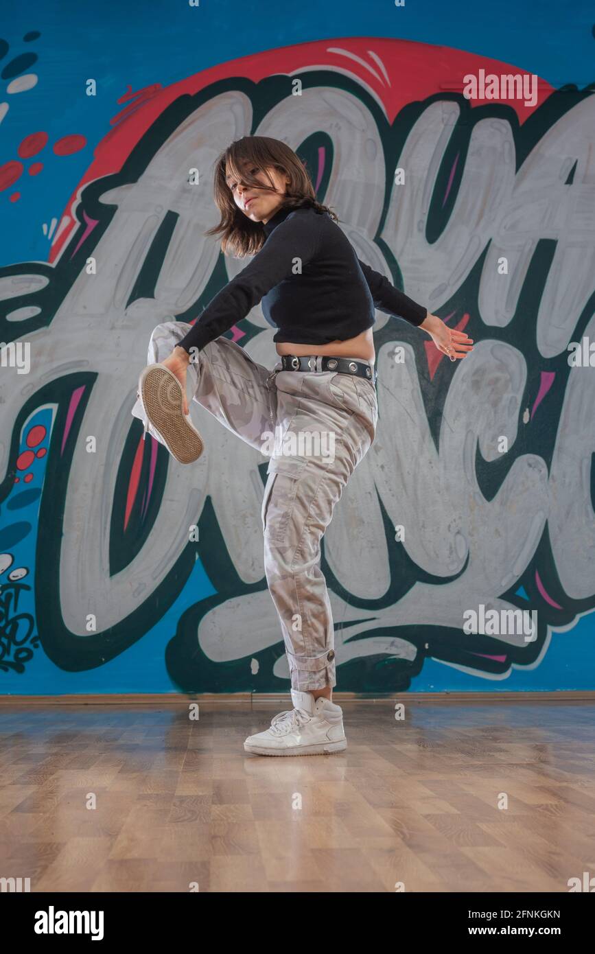 Attractive young woman doing breakdance move over graffiti background ...