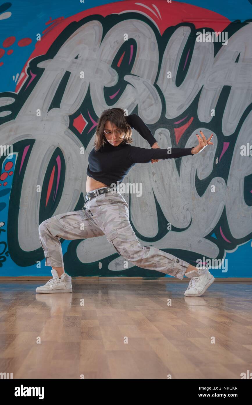 Attractive young woman doing breakdance move over graffiti background ...