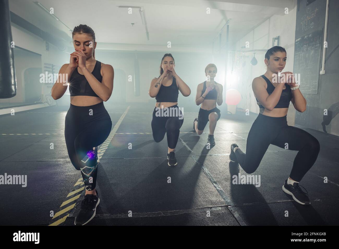 Group of sportswomen in sportswear doing lunge exercise at the gym with ...