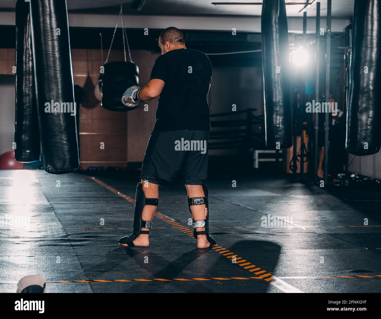 Silhouette male boxer hitting a huge punching bag at a boxing studio ...