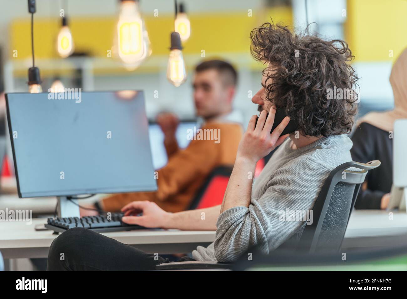 Bearded employee guy with afro haircut talking on his phone while being ...