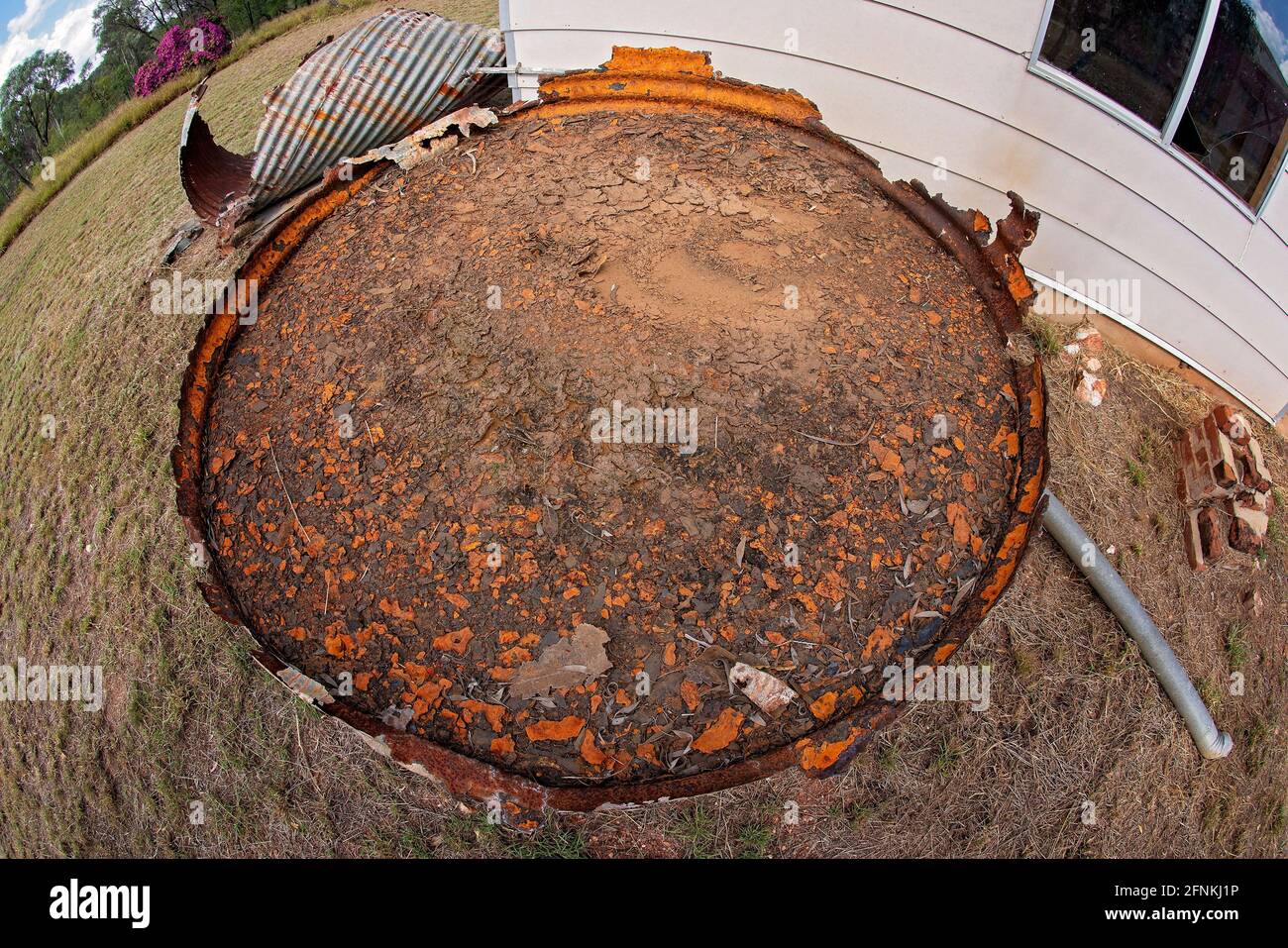 An old rusted water tank filled with dirt and sheet of iron, circular ...