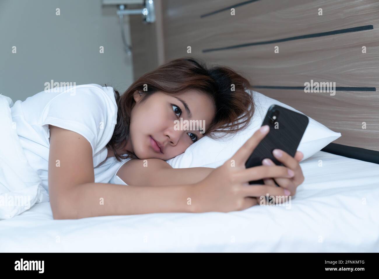 Young asian women lying in bed texting and checking social apps in ...