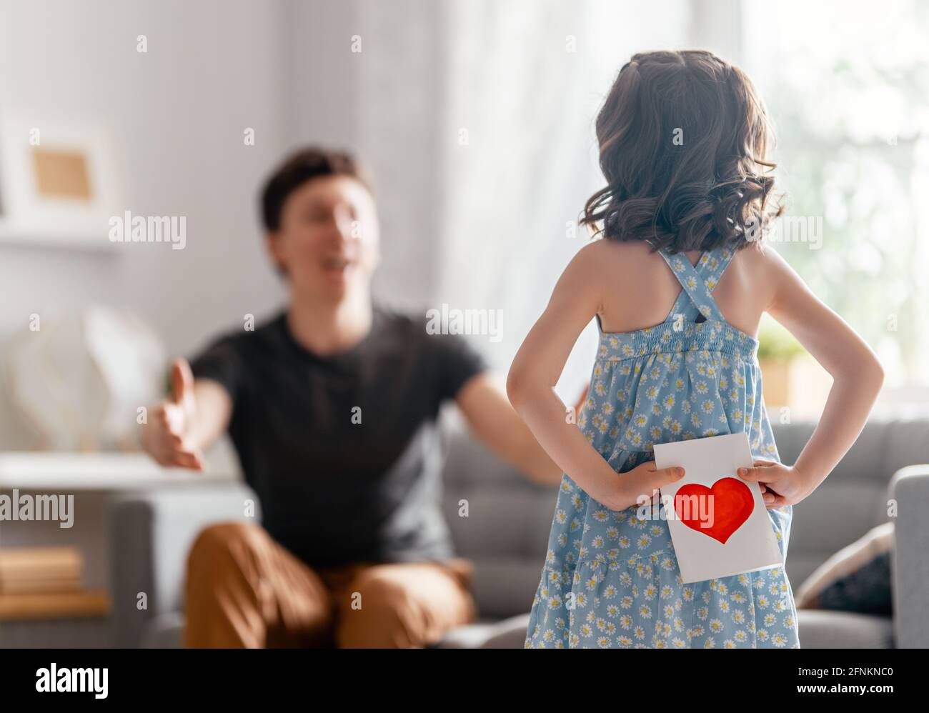 Child daughter is congratulating her father and giving him postcard ...