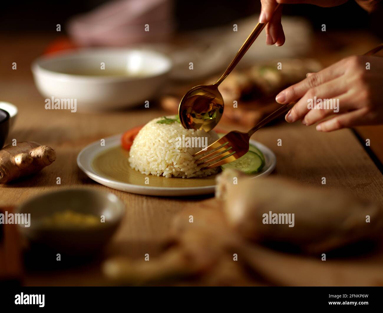 Close-up view of woman eating Hainanese chicken rice (steamed chicken ...