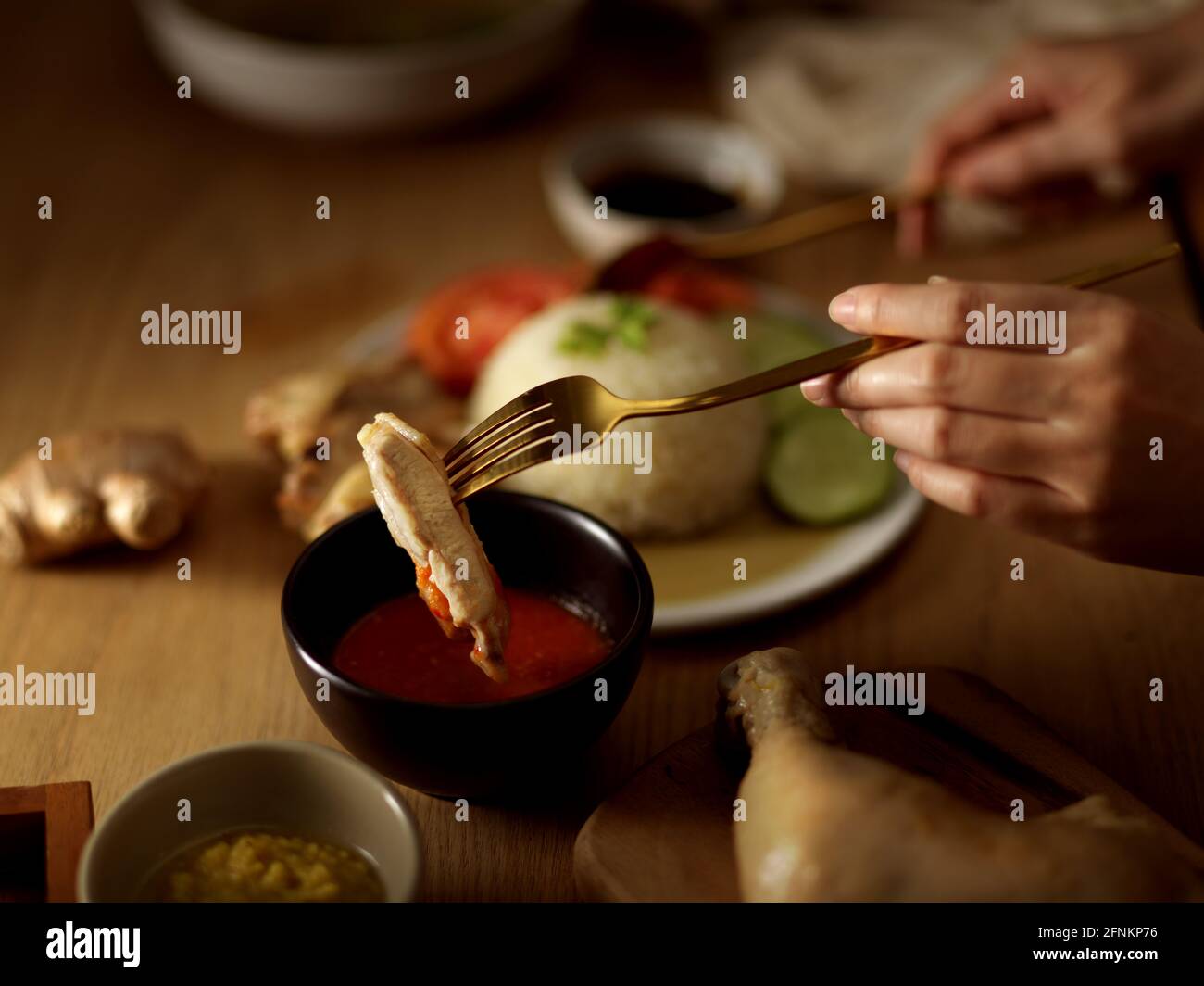 Close-up view of woman eating Hainanese chicken rice (steamed chicken ...