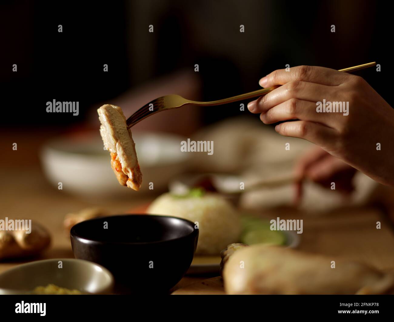 Close-up view of woman eating Hainanese chicken rice (steamed chicken ...