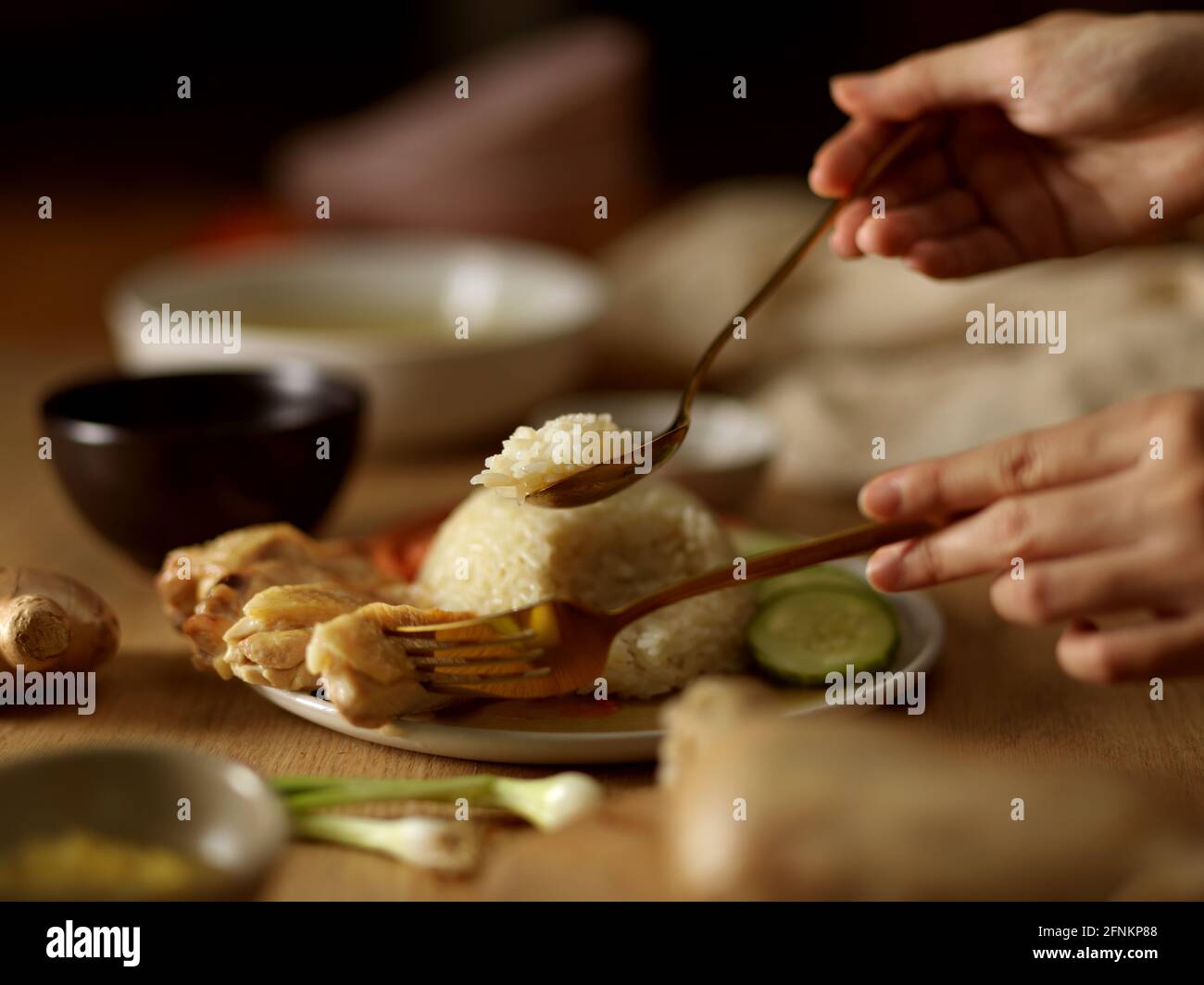 Close-up view of woman eating Hainanese chicken rice (steamed chicken ...