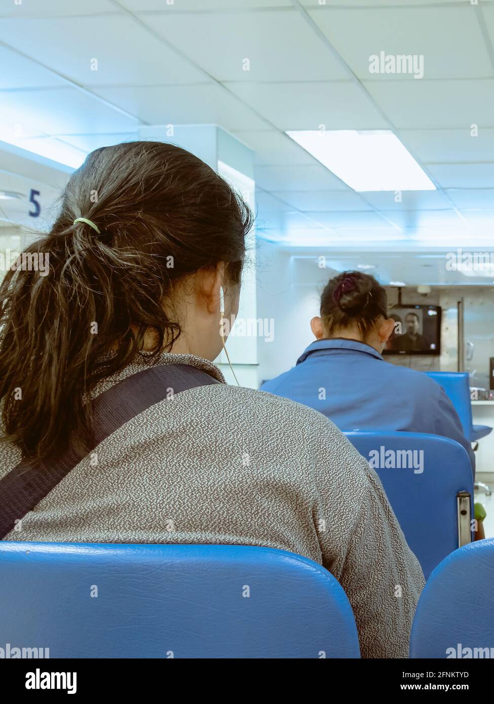 Back view of female customers sitting and wait in queues to financial ...