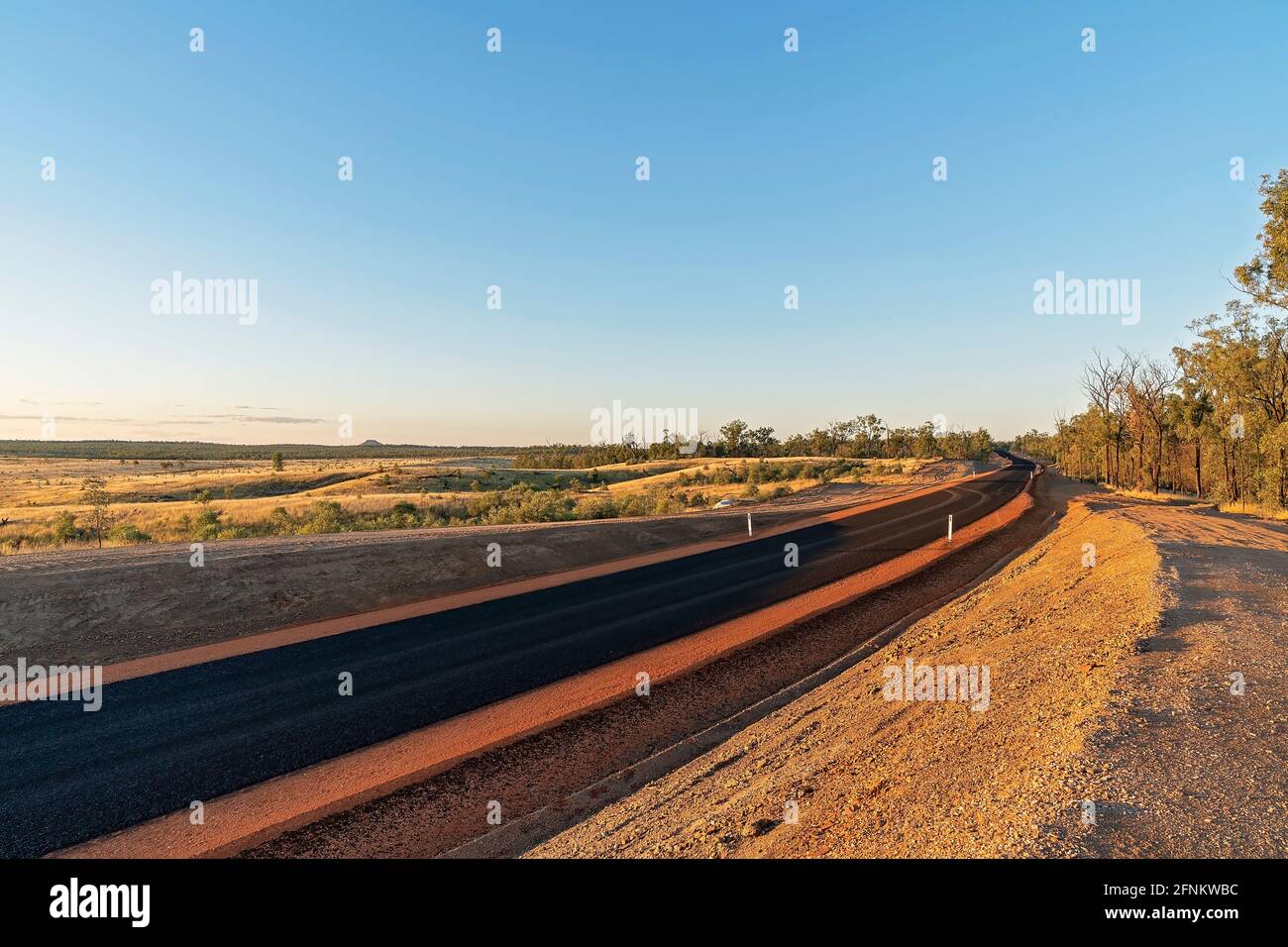 A country road with built up sides in outback Australia at sunset Stock ...