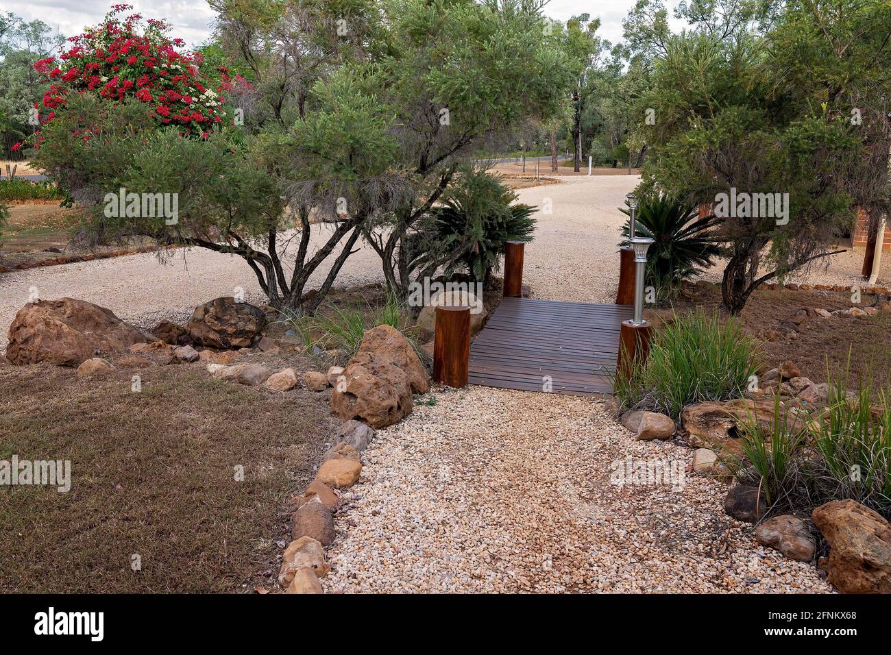Pebble pathway and small timber bridge crossing in a country garden ...