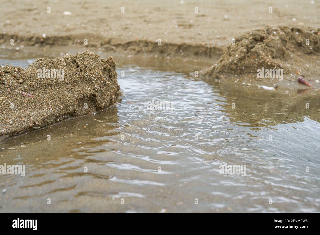 Sand dam and sea water flow on the beach by the sea Stock Photo - Alamy