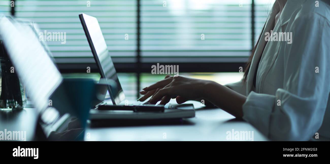 Side view of female hand typing on laptop keyboard while working on ...