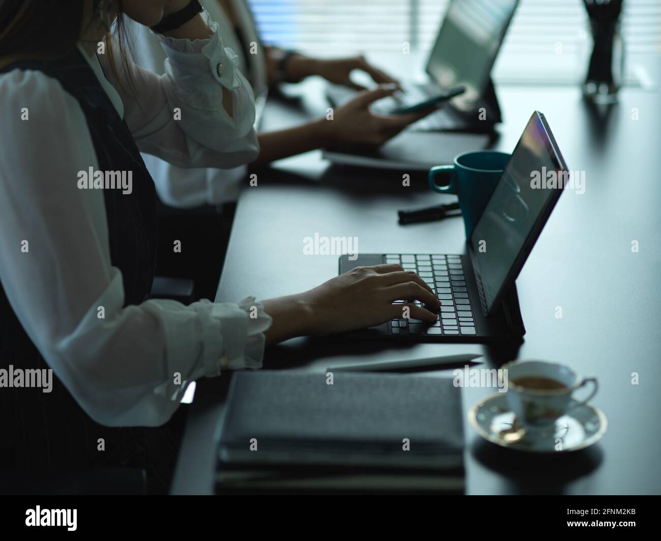Side view of two female workers working together with office supplies ...