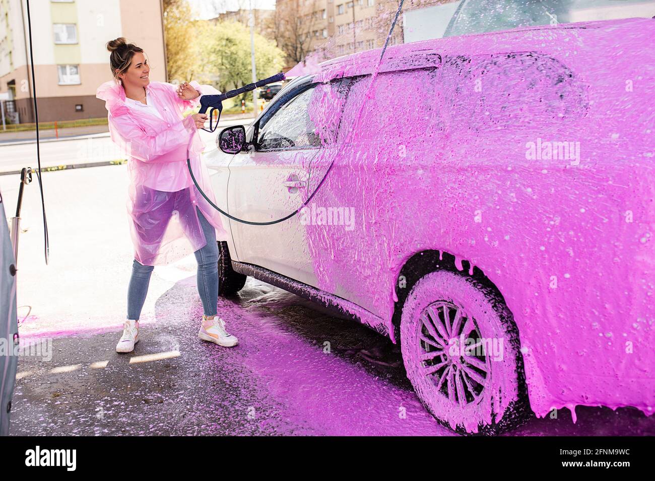 Car in pink foam at self-service car wash, woman worker happily doing ...